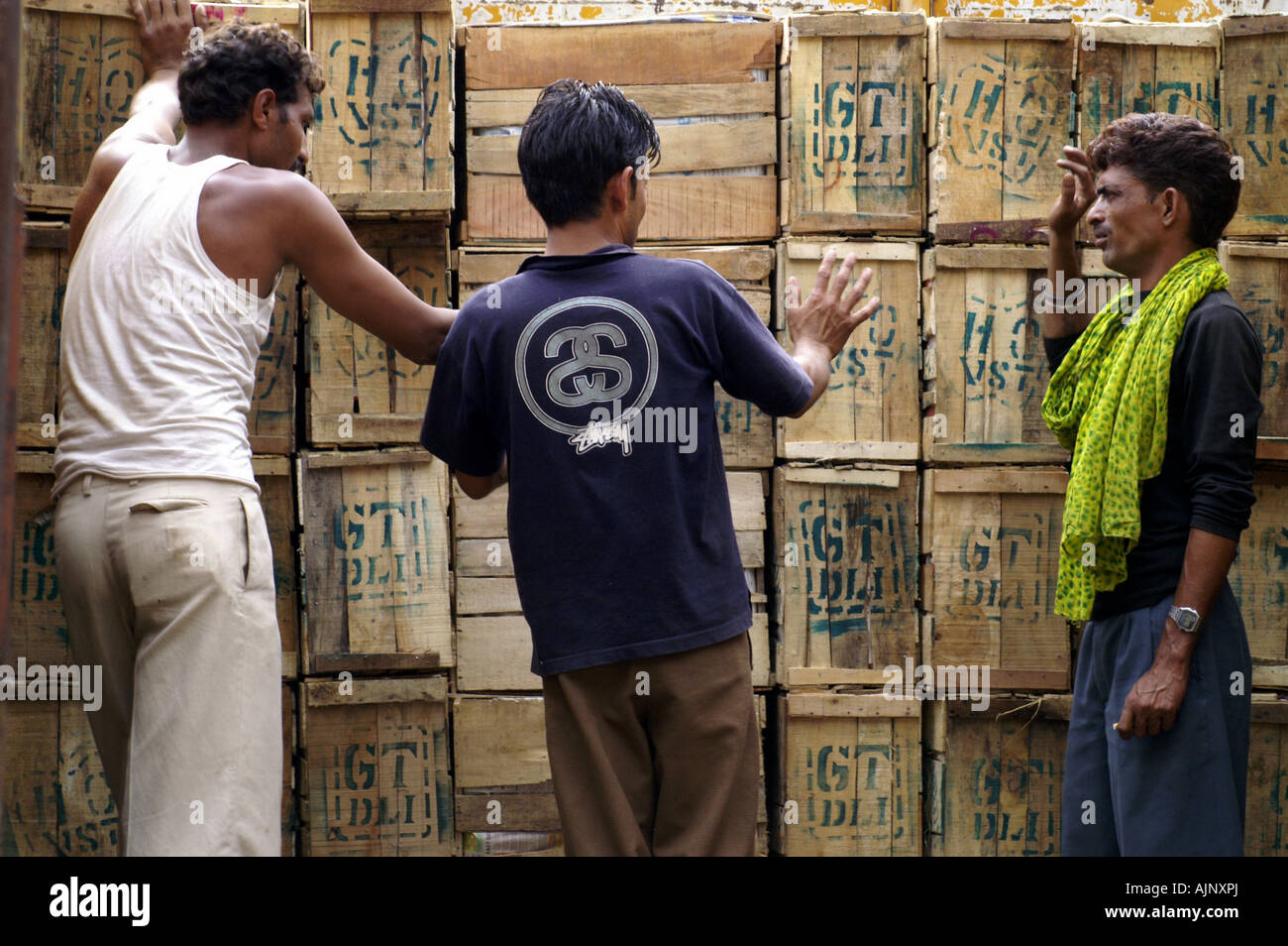 Three indian men stackig apple wooden crates boxes truck load manual ...