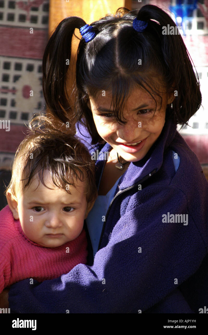 Happy smiling young Indian girl child kid taking care hugging younger ...