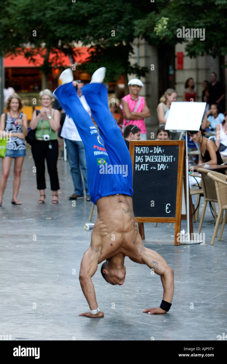 Black man dancer performs on a street - balances on hands with feet up ...