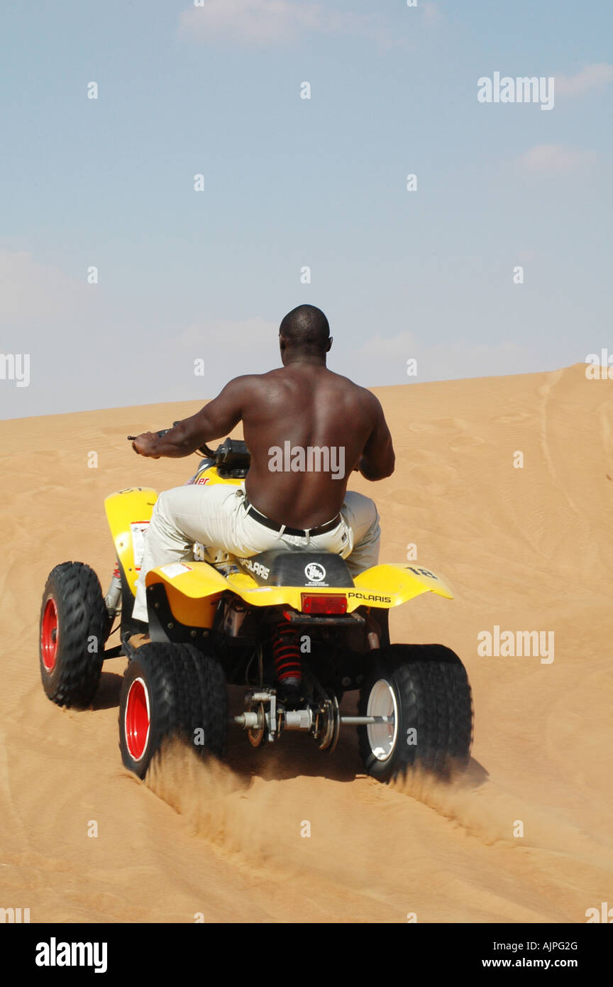Rear view of a man riding a quad bike in a desert Stock Photo - Alamy
