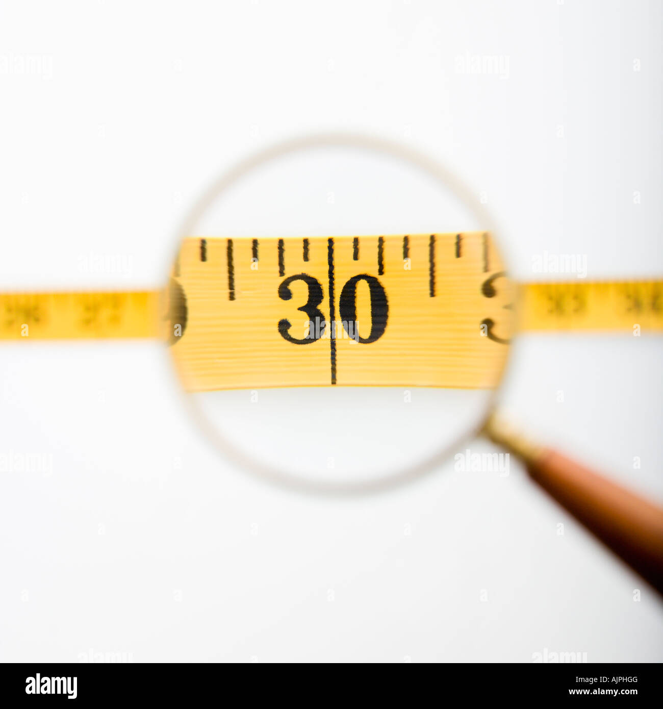 Magnifying glass held over measuring tape Stock Photo - Alamy