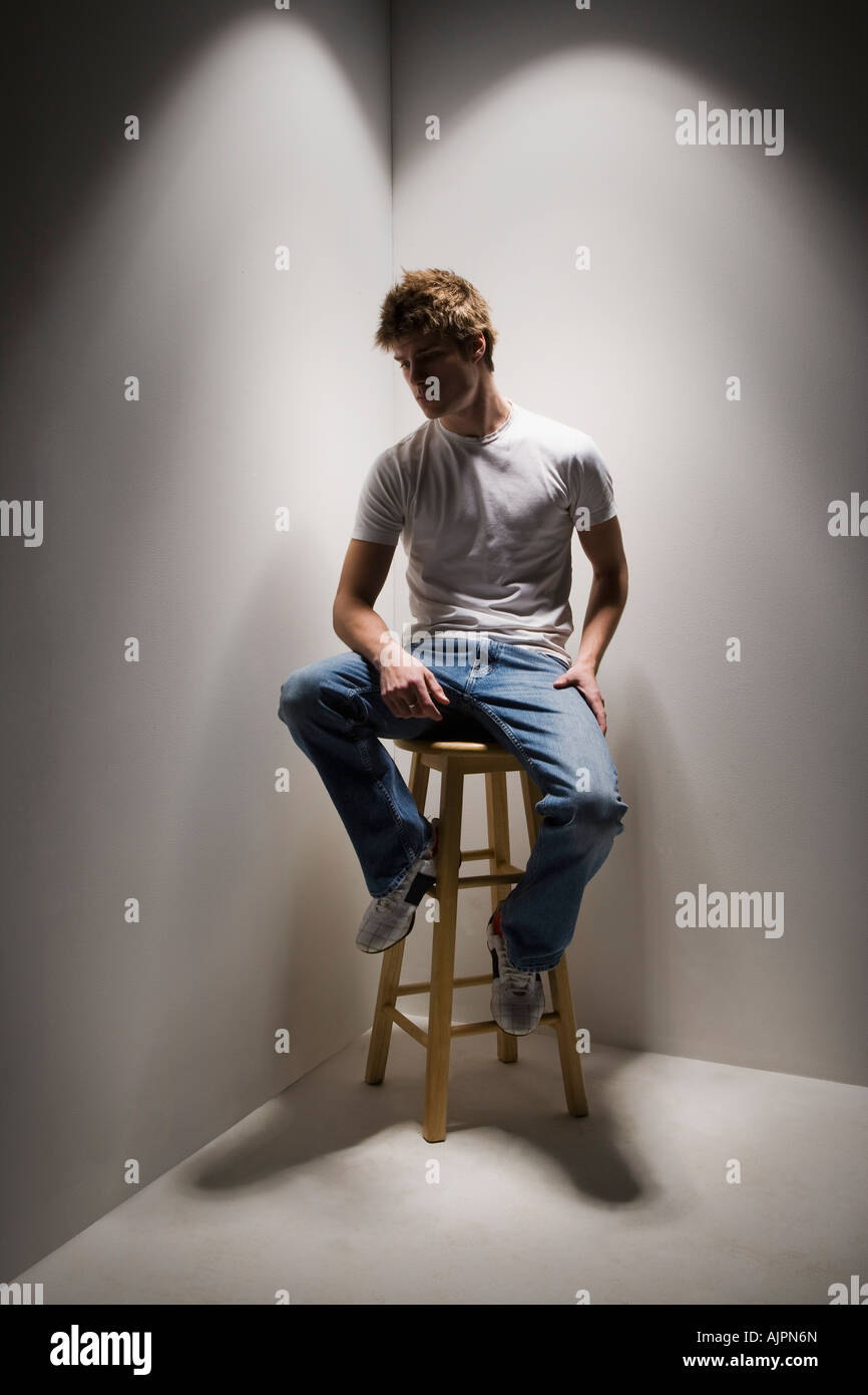 Young man sitting on a stool Stock Photo - Alamy