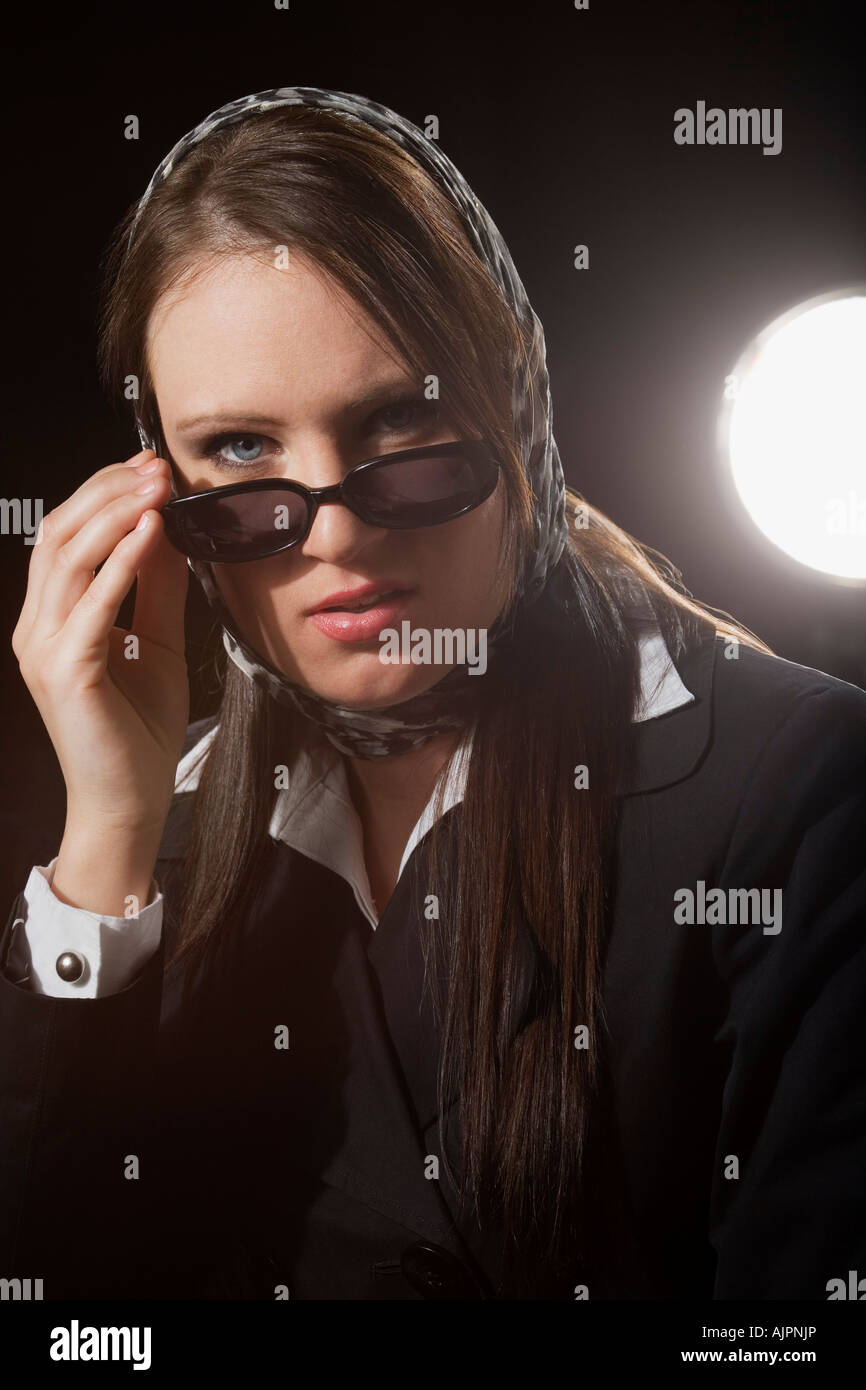 A young woman peering over sunglasses Stock Photo - Alamy