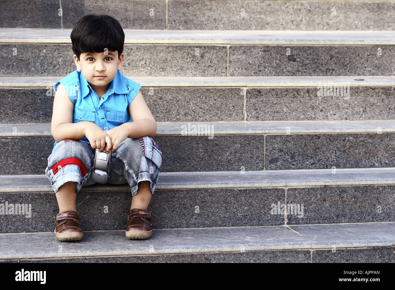 Young boy sitting on the steps Stock Photo - Alamy