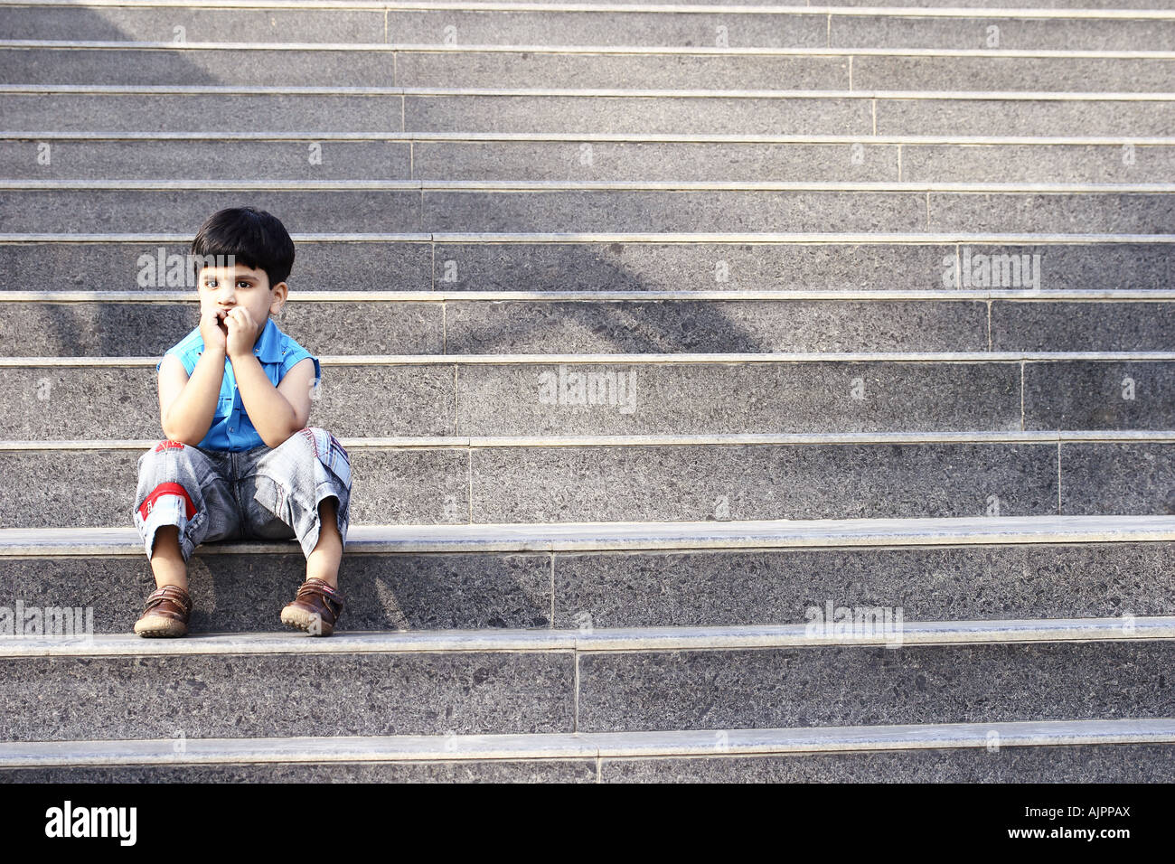 Young boy sitting on steps Stock Photo - Alamy