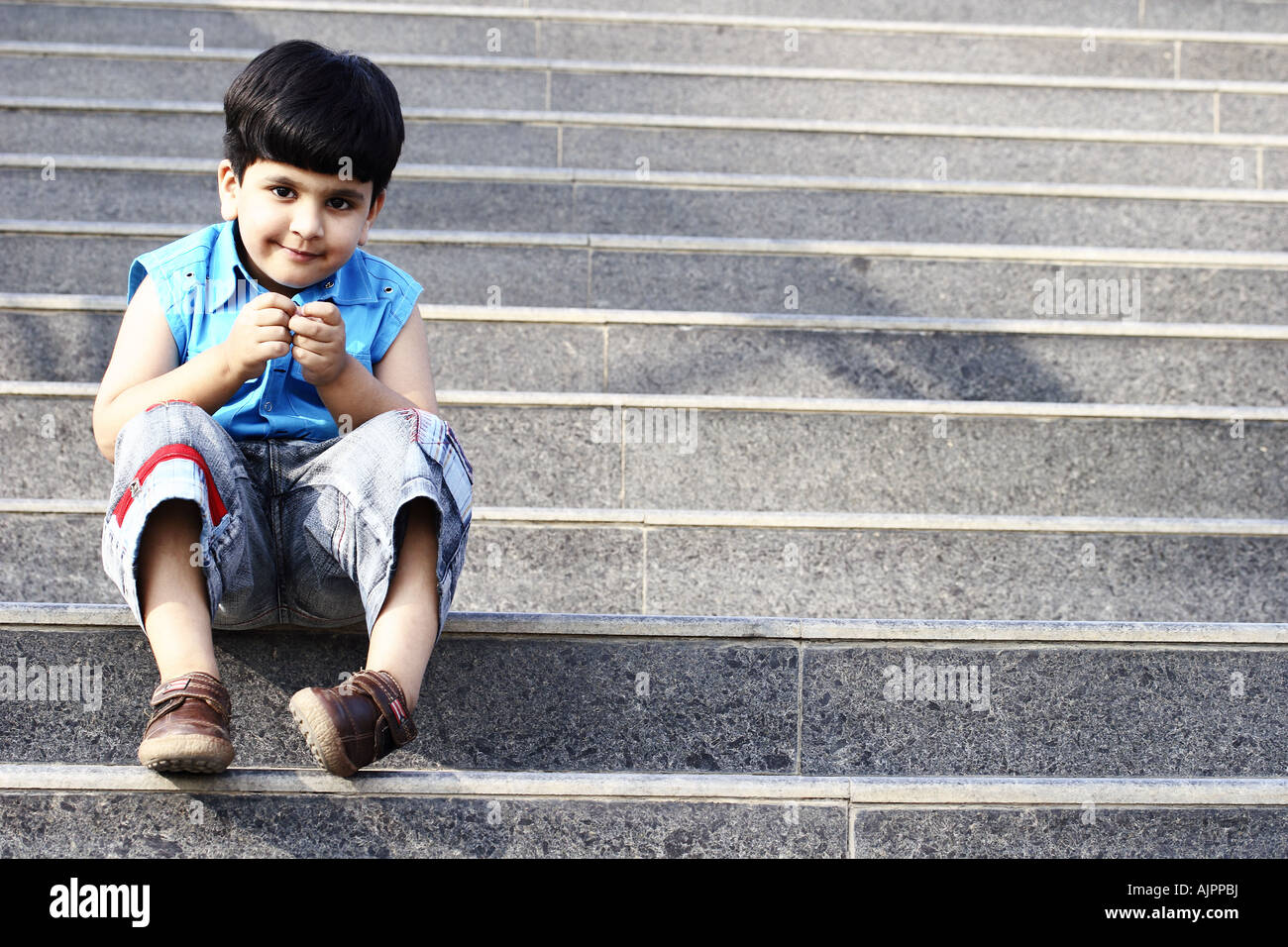 Young boy sitting on steps Stock Photo - Alamy