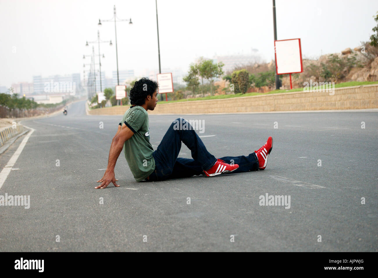 A man sitting alone on a road Stock Photo - Alamy