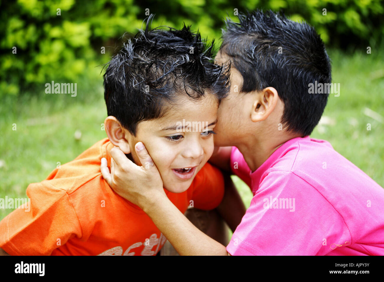 A young kid whispering into his friends ear Stock Photo - Alamy
