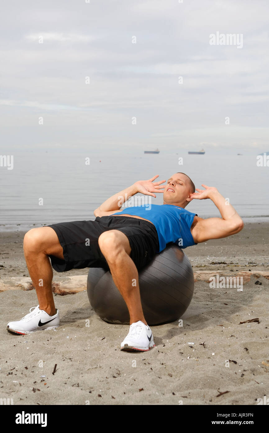 fit muscular hard body male personal trainer exercising with a ball ...