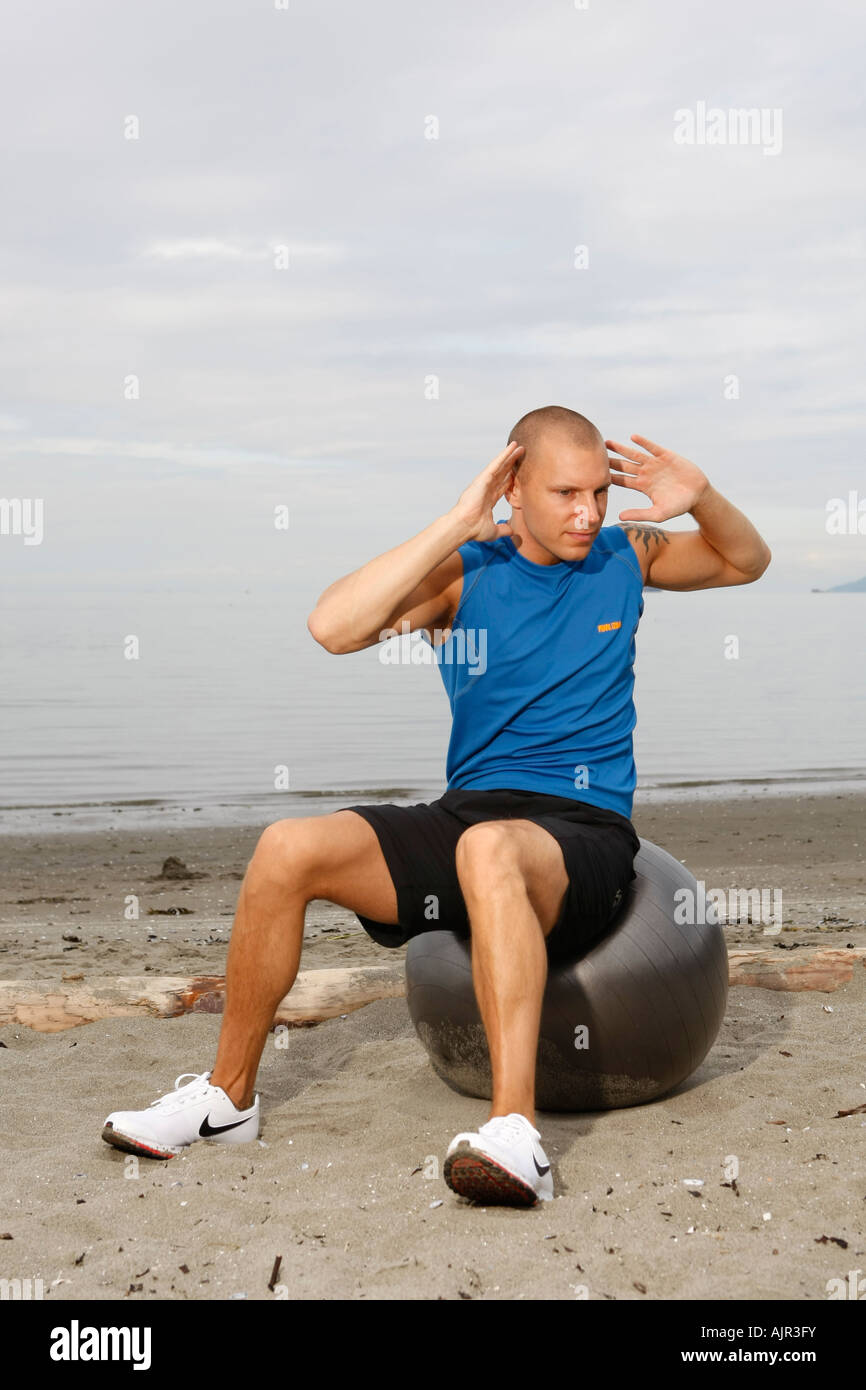 fit muscular hard body male personal trainer exercising with a ball ...