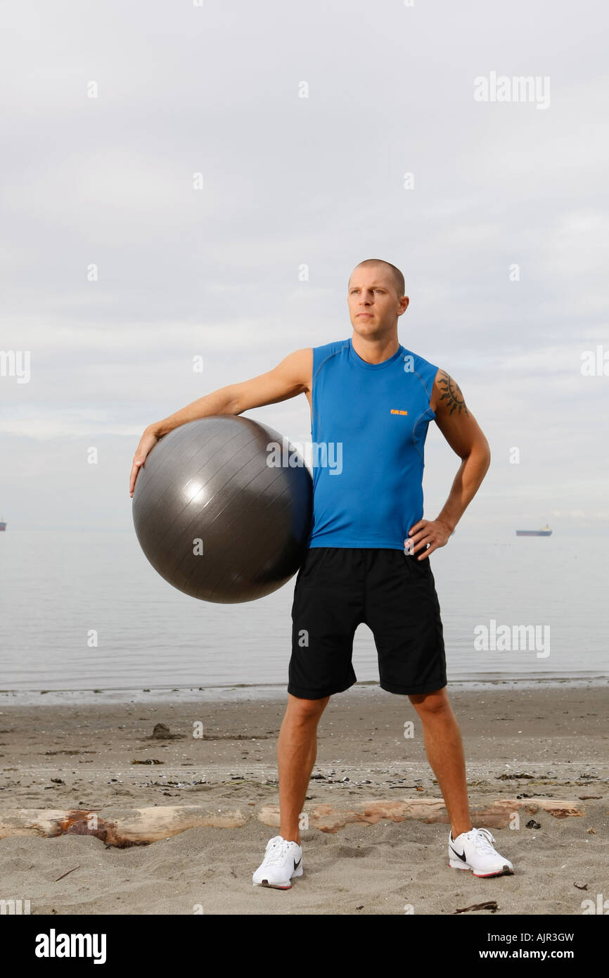 fit muscular hard body male personal trainer exercising with a ball ...