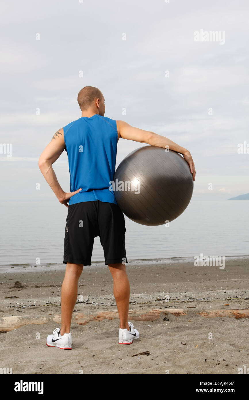 fit muscular hard body male personal trainer exercising with a ball ...