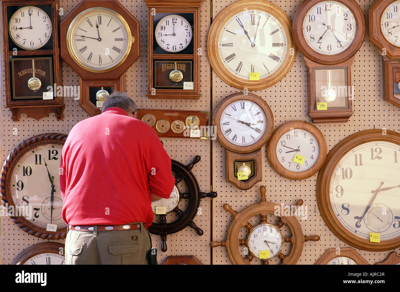 A man in front of a display of clocks at an outdoor summer festival in ...