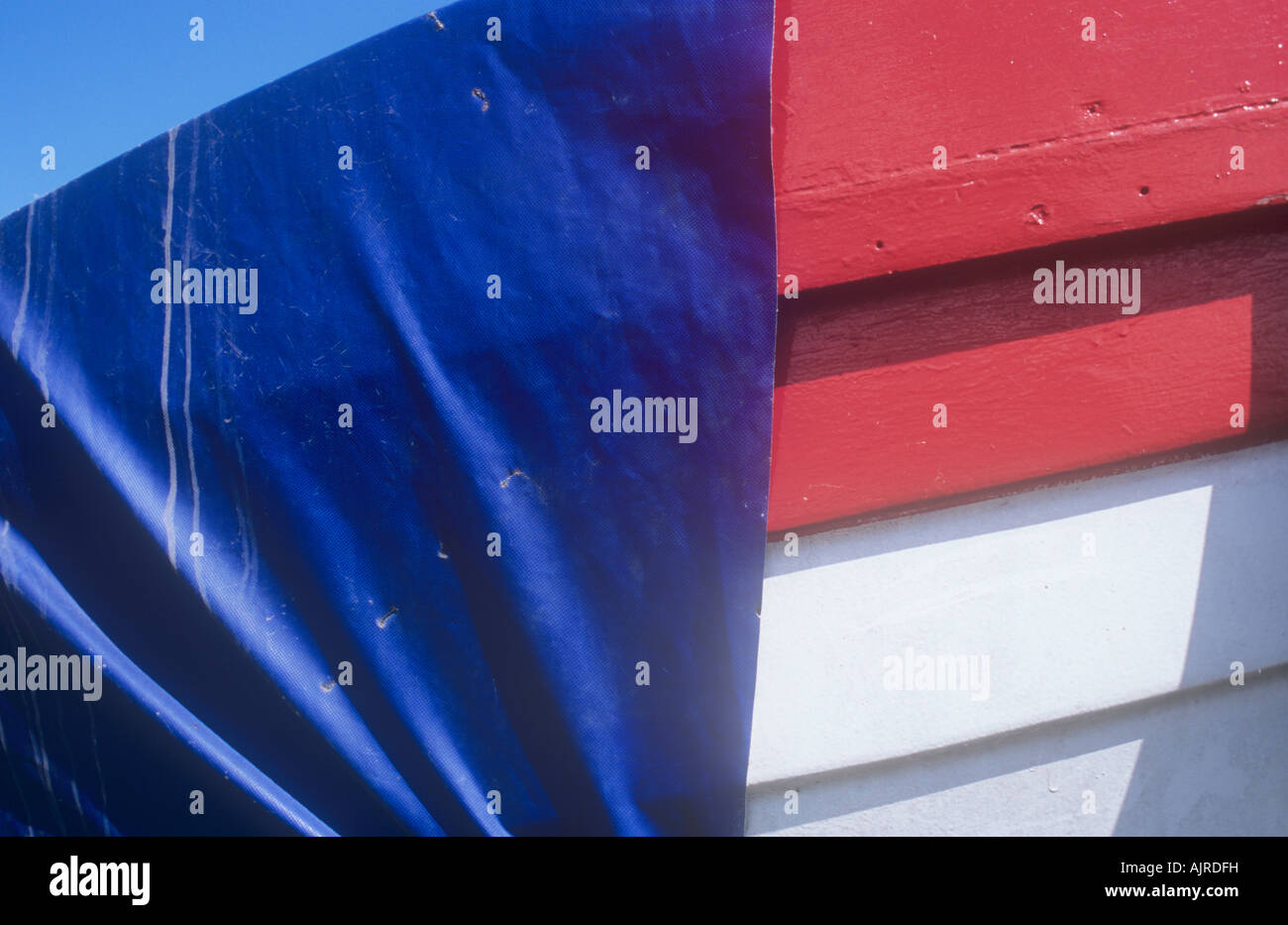 Detail of hull of wooden boat painted scarlet red and white with dark ...