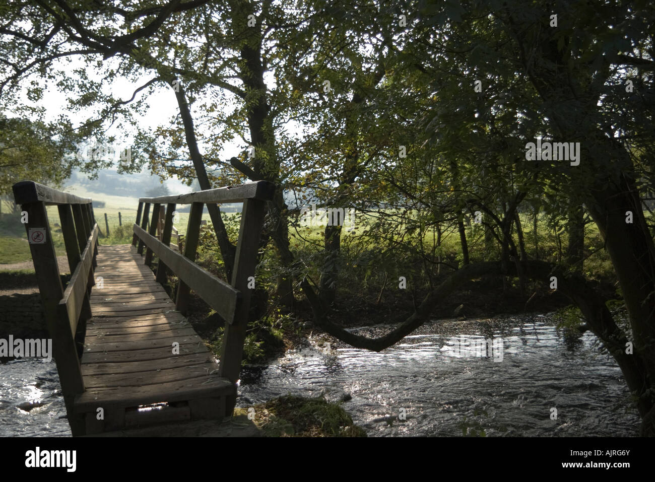 A rustic footbridge over the River Dove, Derbyshire on an early autumn ...