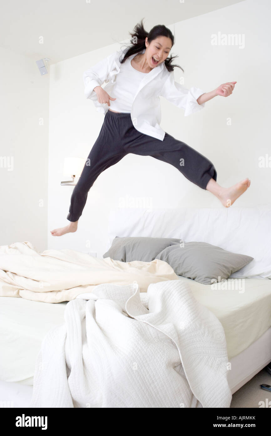 Young woman jumping on the bed Stock Photo - Alamy