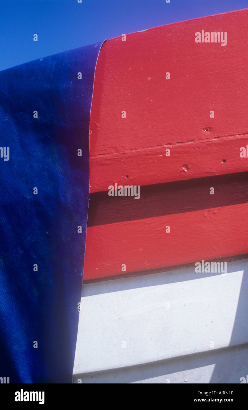 Detail of hull of wooden boat painted scarlet red and white with dark ...