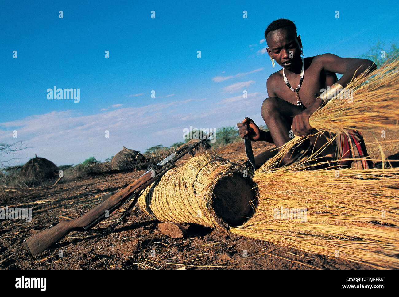Hamer man making a beehive by dried grass, Omo river region Ethiopia ...