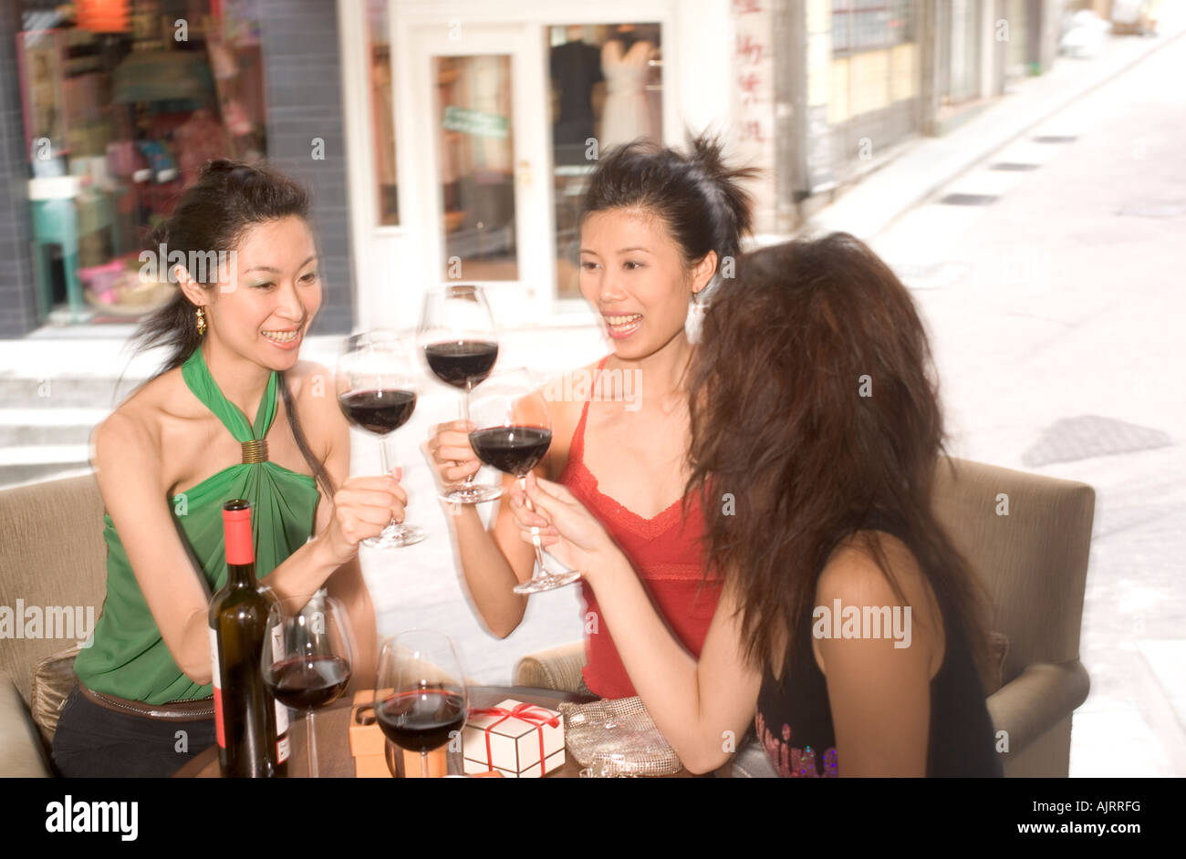 Three young women raising a toast Stock Photo - Alamy