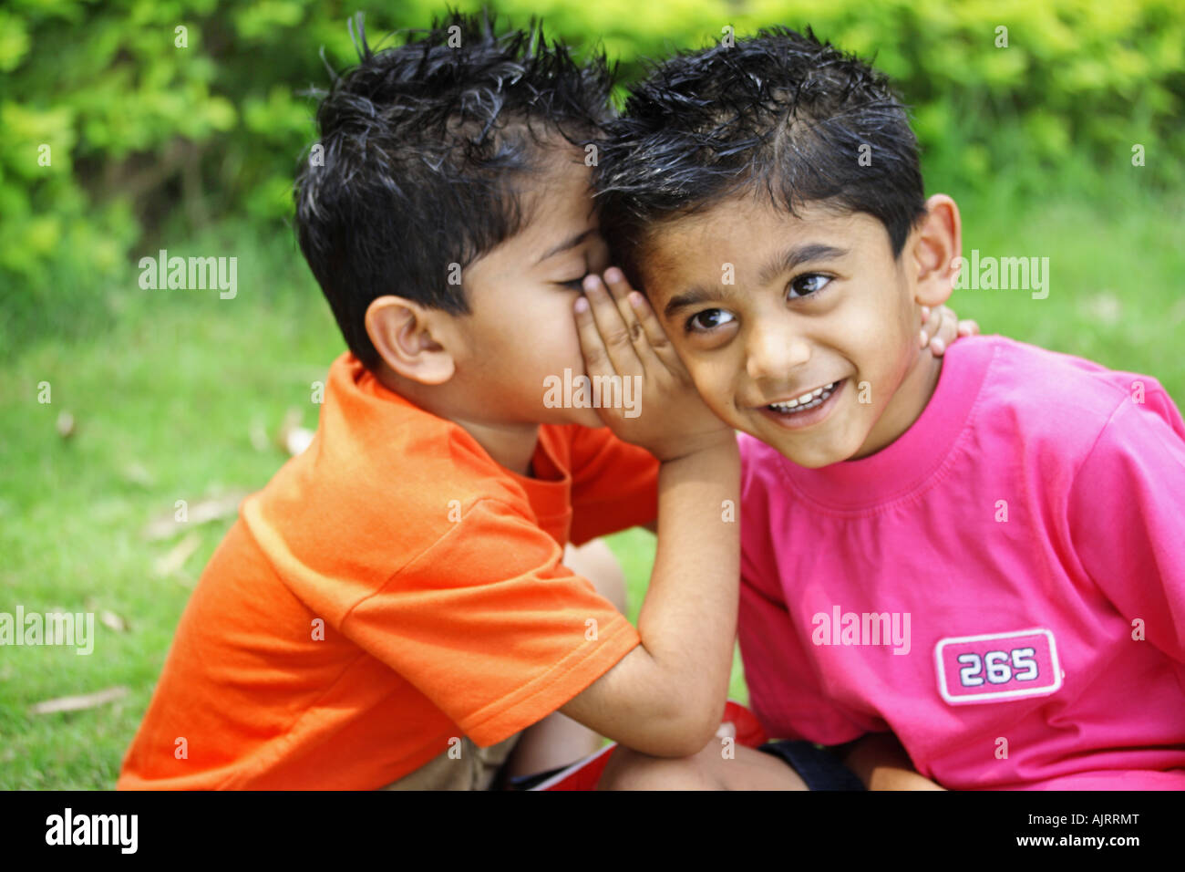 A young kid whispering into his friends ear Stock Photo - Alamy