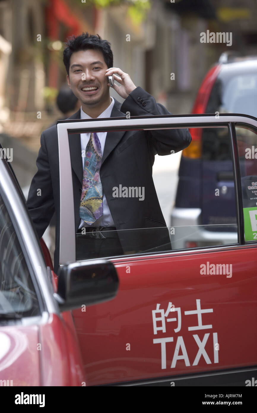 Businessman on cell phone next to cab Stock Photo - Alamy