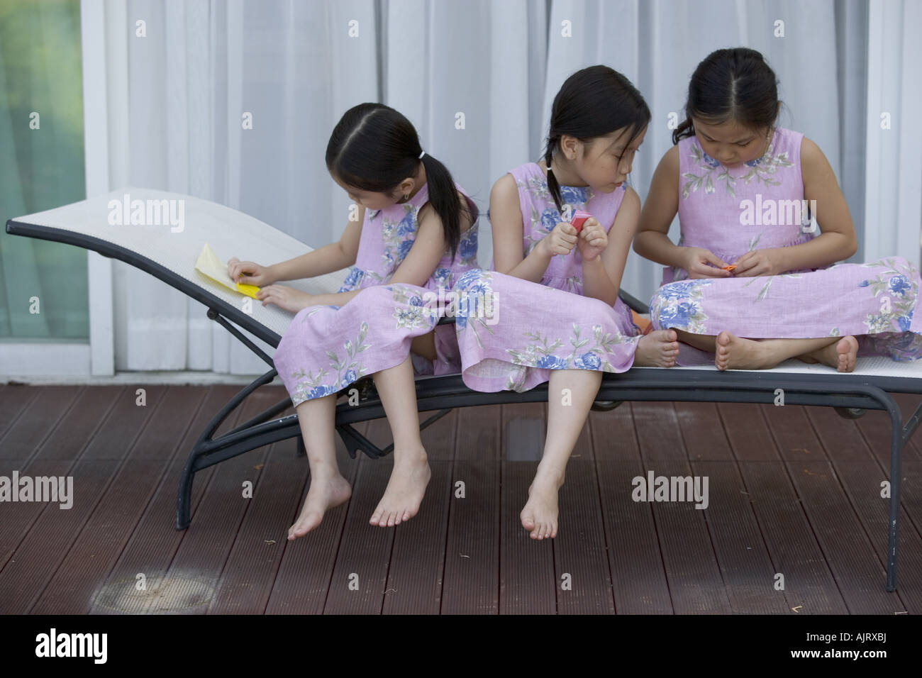 Three girls making paper boats Stock Photo - Alamy