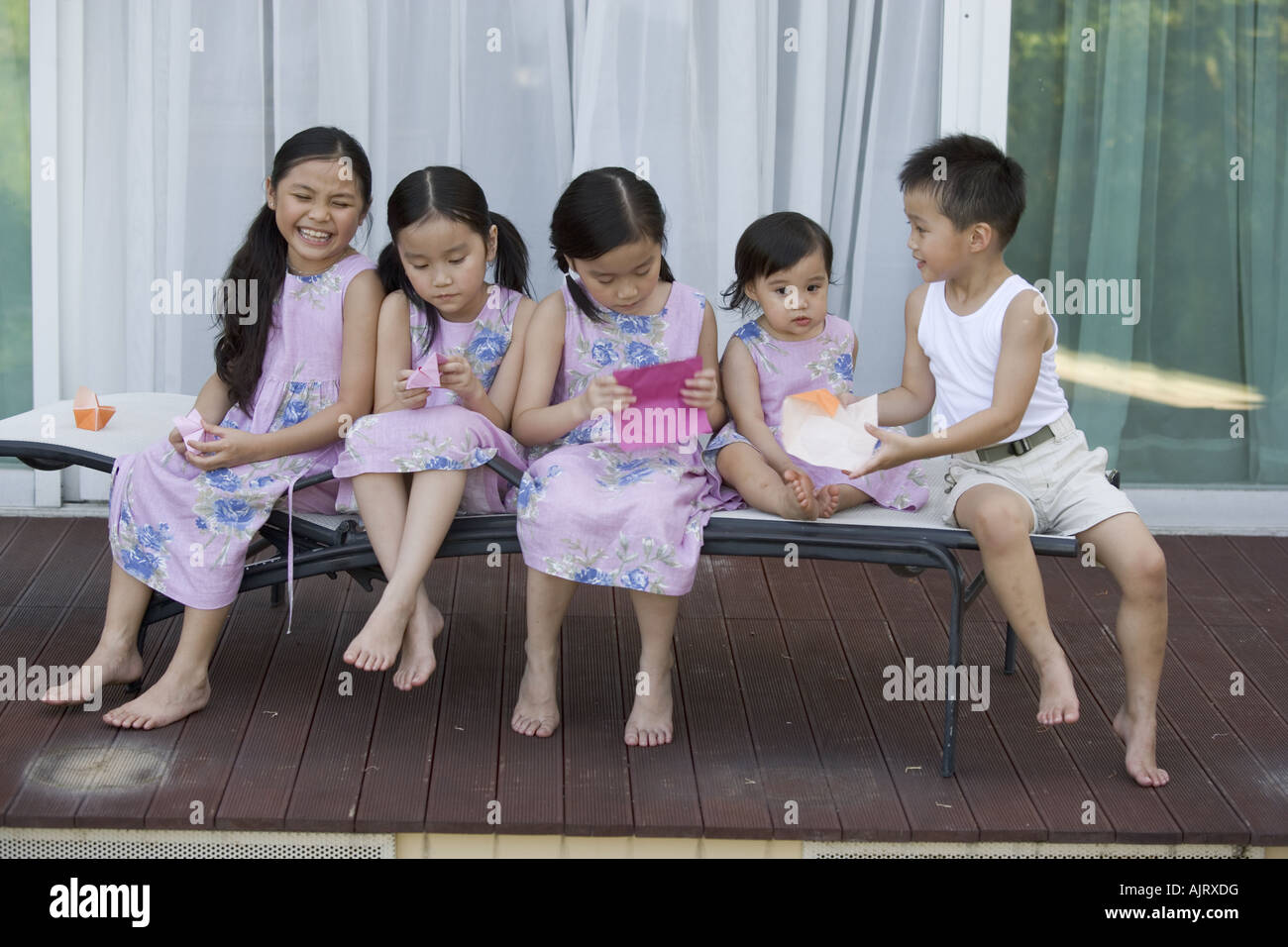 Five children sitting together on a chaise lounge Stock Photo - Alamy