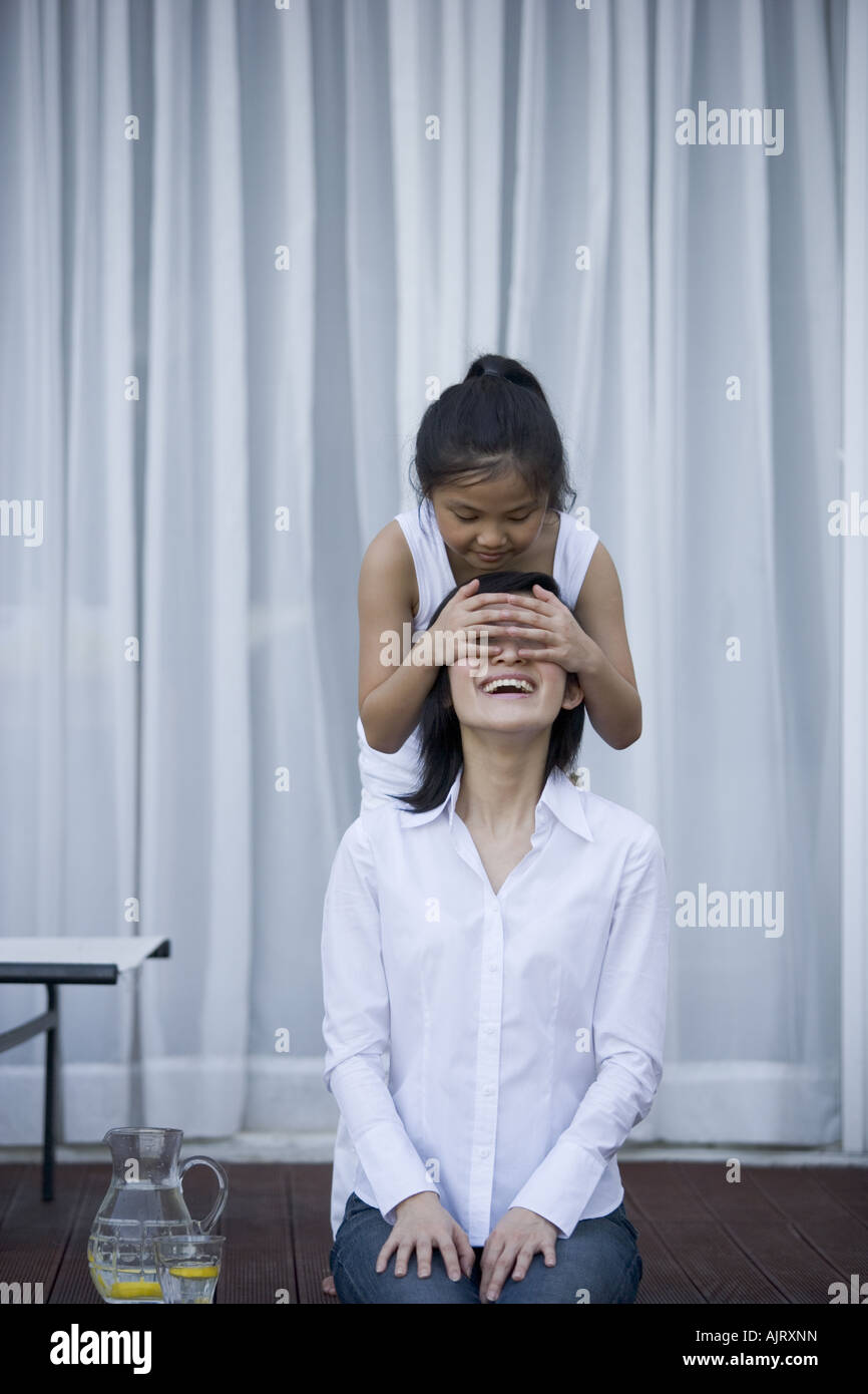 Girl covering her mother's eyes with her hands Stock Photo - Alamy