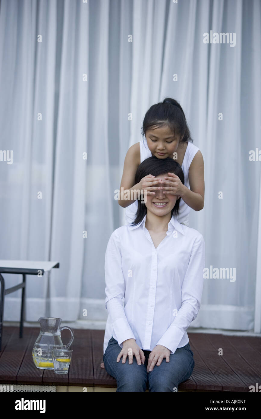 Girl covering her mother's eyes with her hands Stock Photo - Alamy