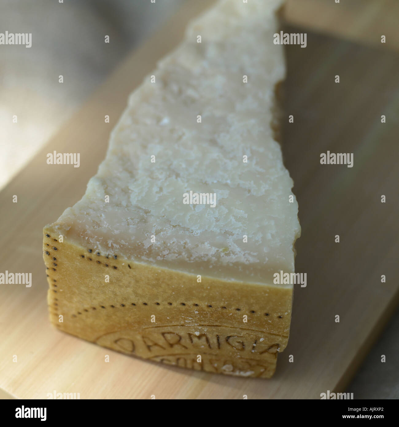 Parmesan wedge on pale wood chopping board Stock Photo - Alamy