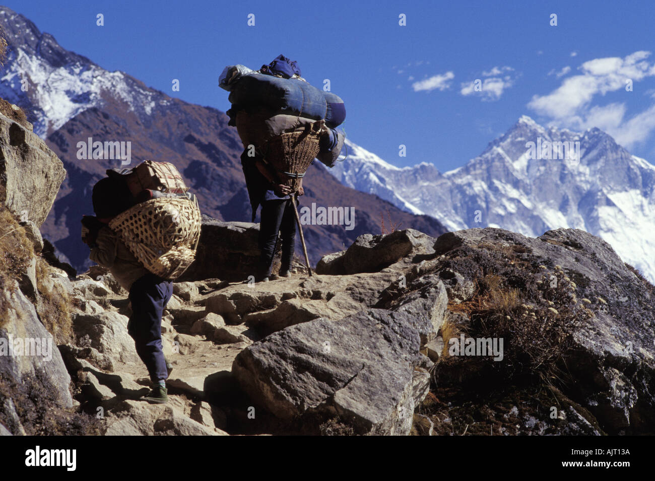 Men carrying heavy loads up mountain Stock Photo - Alamy