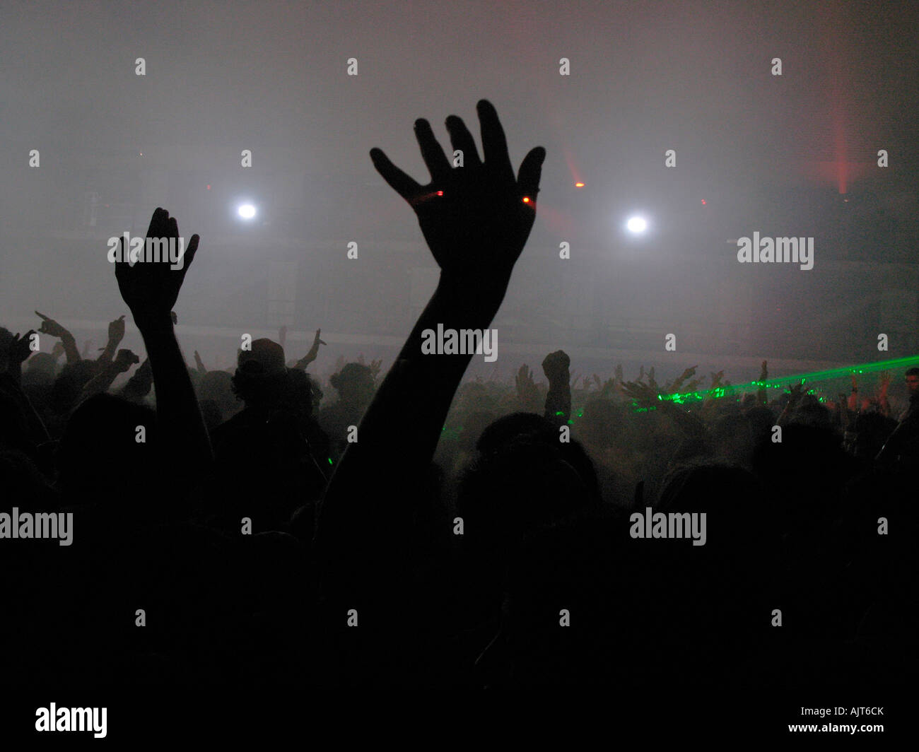 Party goers wave their hands in the air as laser lights stream across ...
