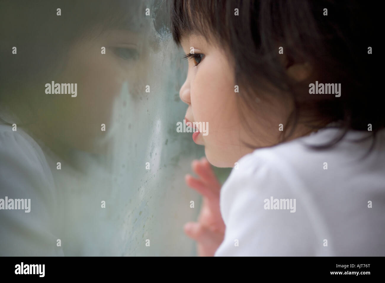 Close-up of a girl looking through a window Stock Photo - Alamy