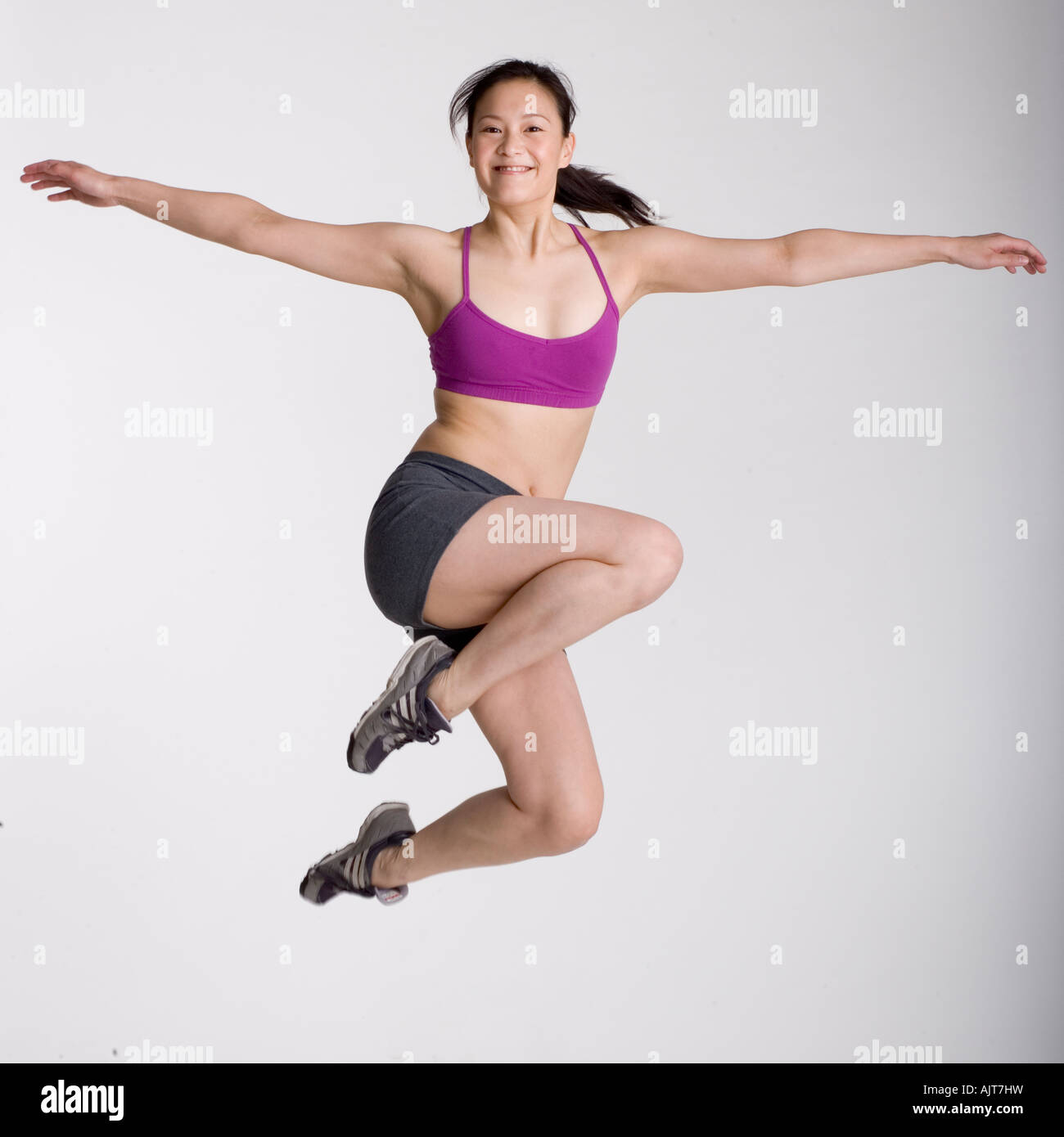 Portrait of a young woman jumping with her arms outstretched Stock ...
