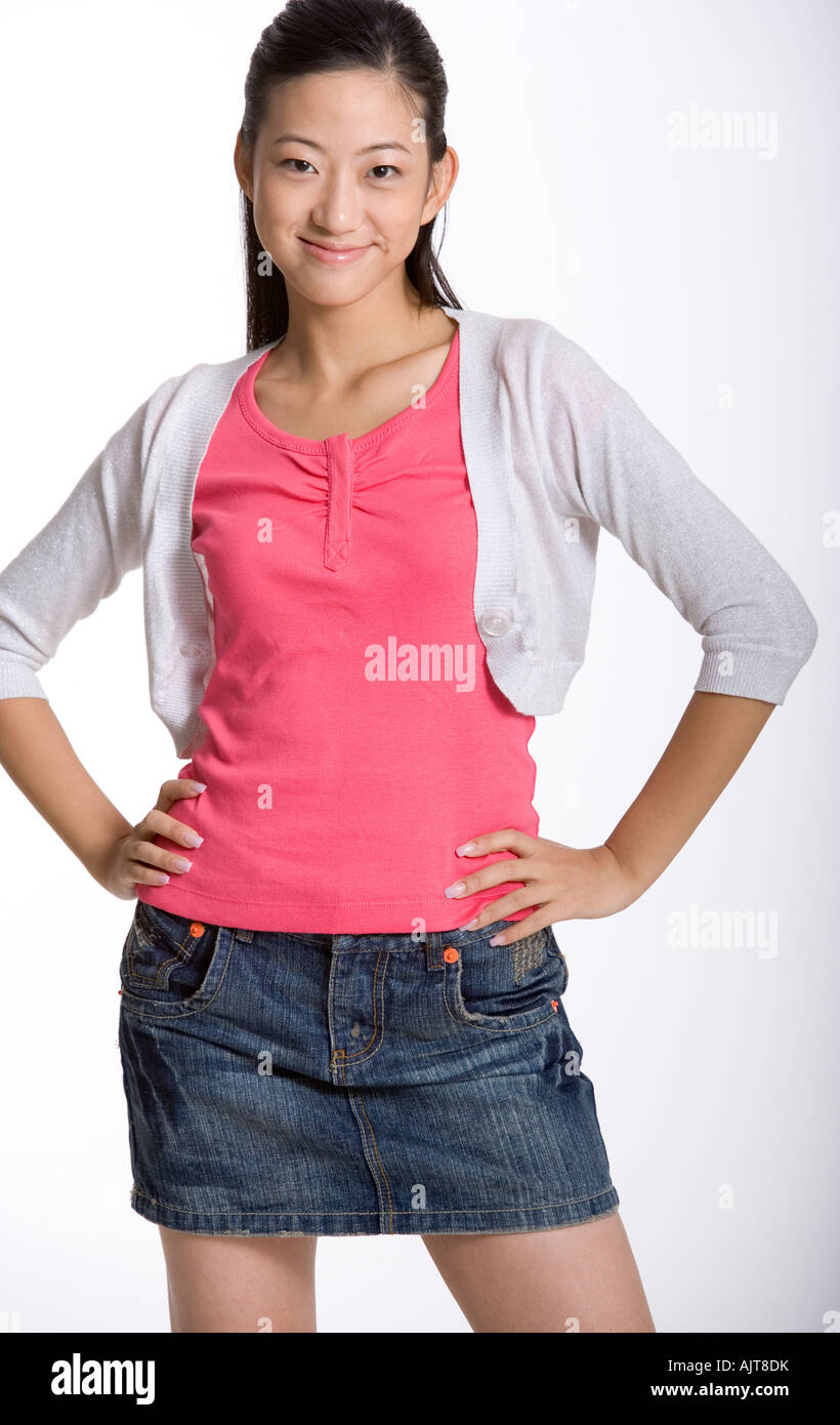Portrait of a young woman standing with arms akimbo and smiling Stock ...