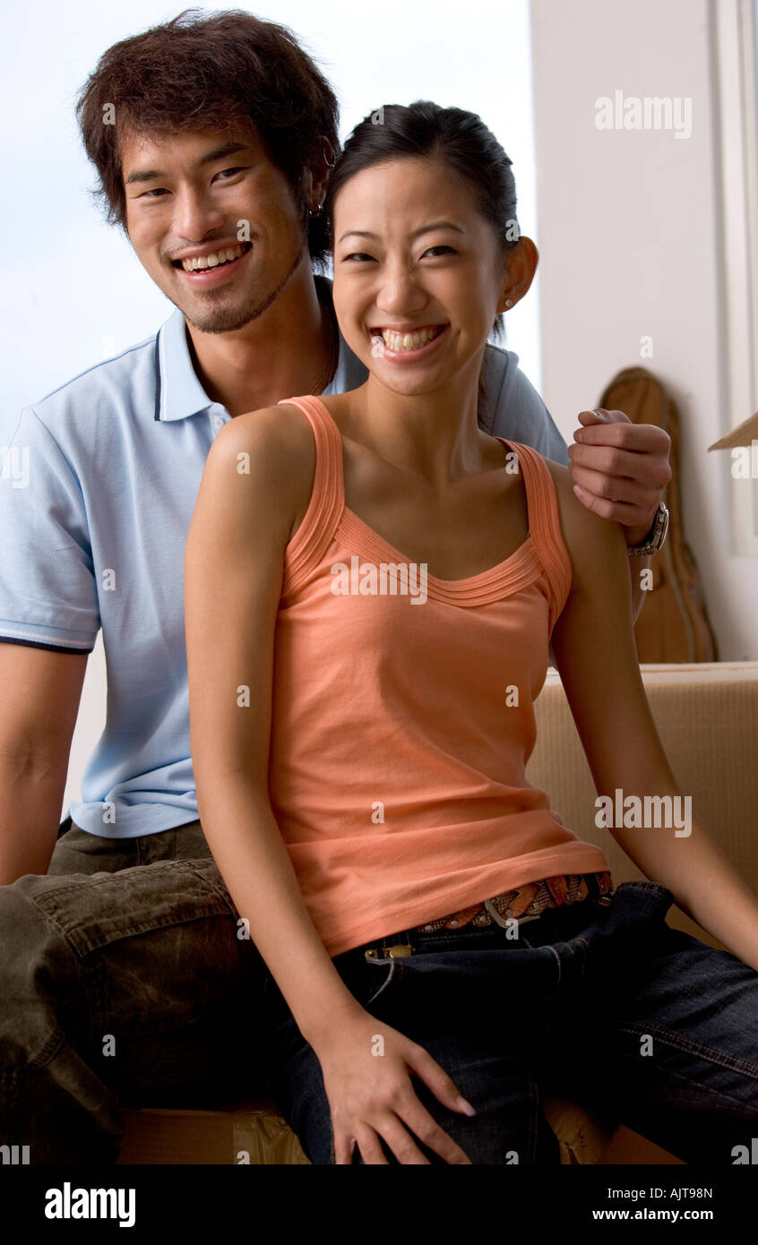 Portrait of a young couple sitting and smiling Stock Photo - Alamy