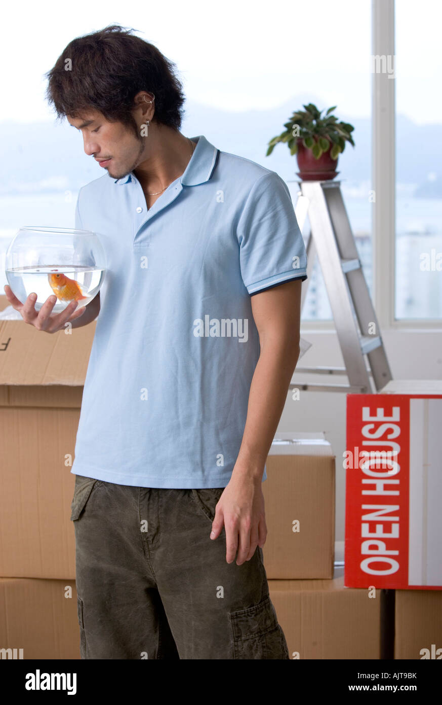 Young man looking at a gold fish in a fish bowl Stock Photo - Alamy