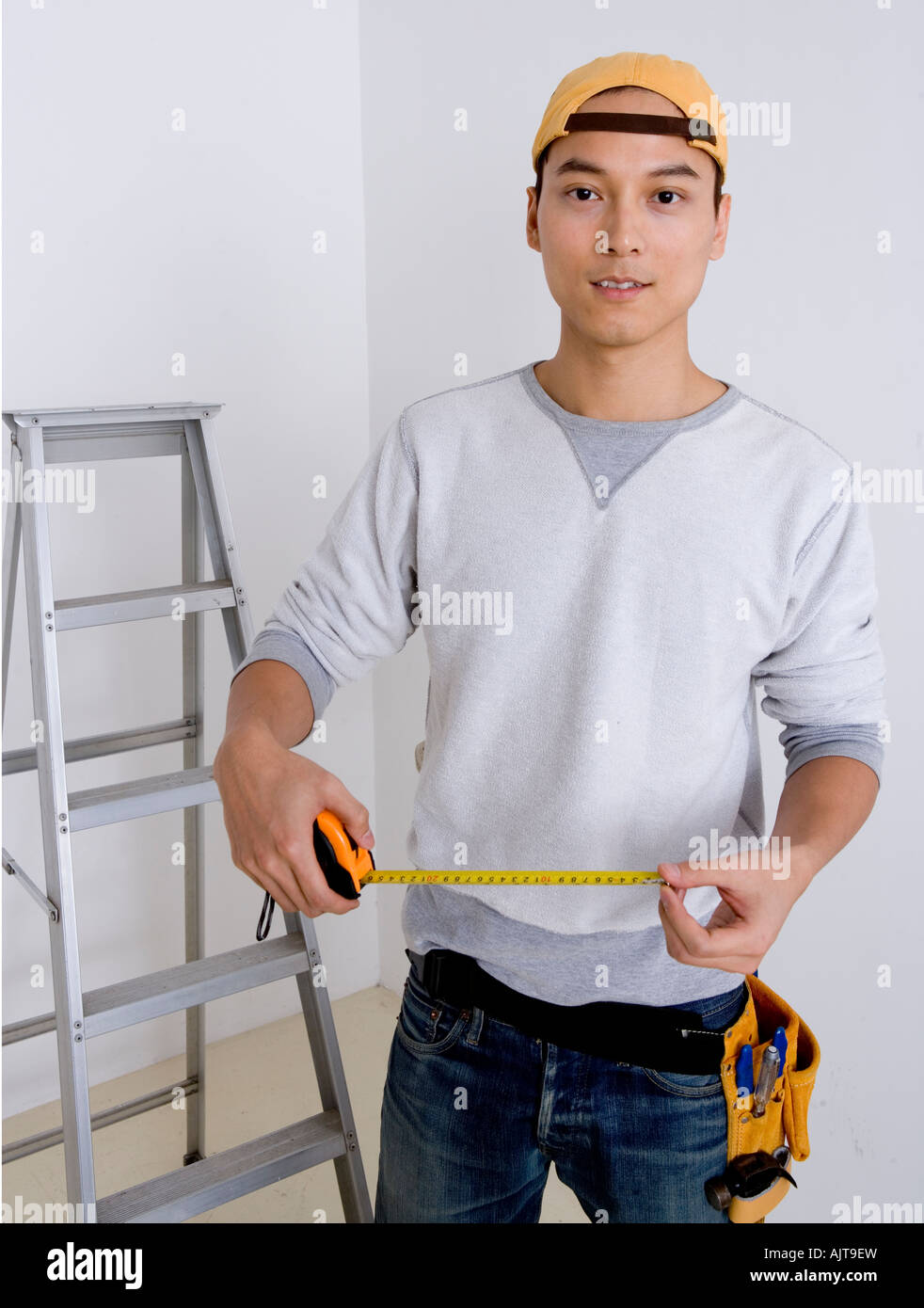 Portrait of a young man standing and holding a tape measure Stock Photo ...