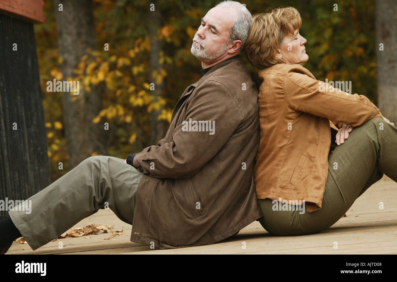 Couple sitting back to back Stock Photo - Alamy