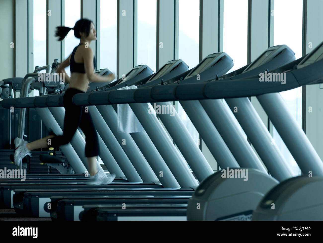 Side profile of a mid adult woman running on a treadmill Stock Photo ...