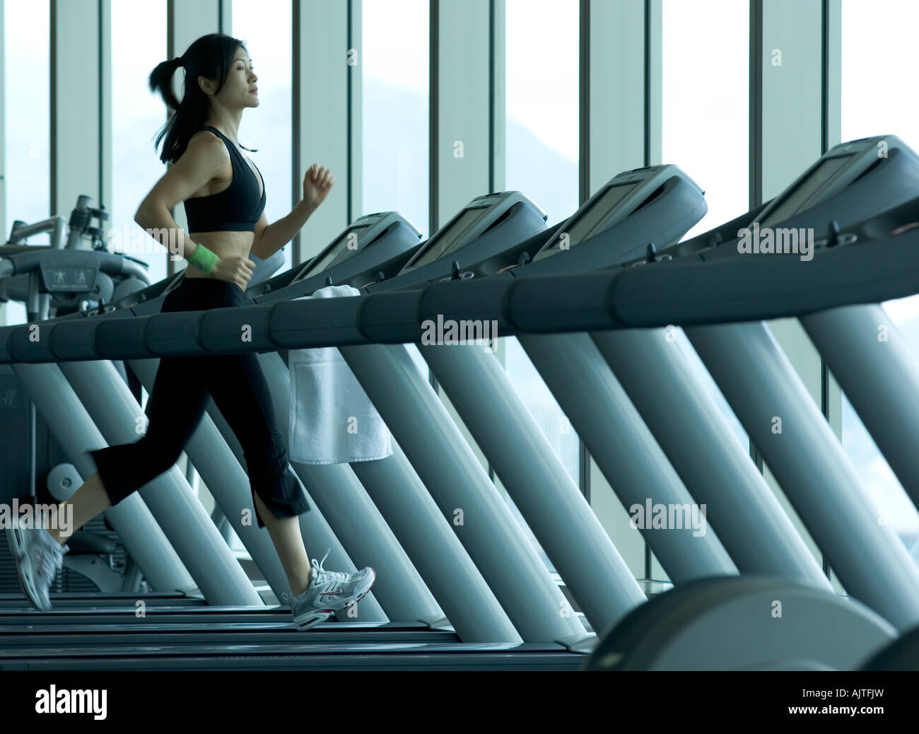 Side profile of a mid adult woman running on a treadmill Stock Photo ...