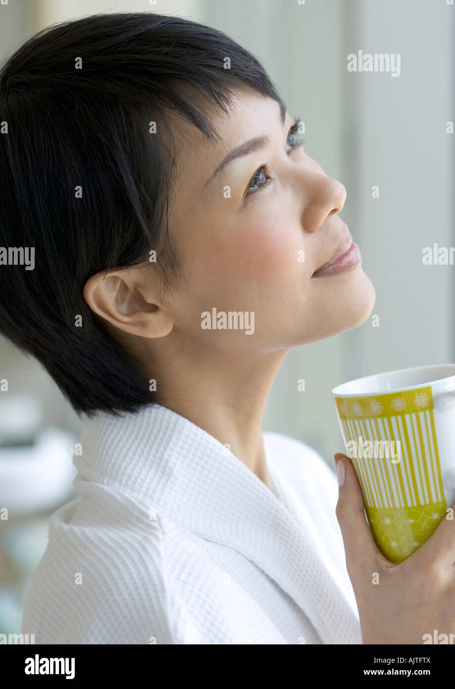 Side profile of a young woman holding a cup of coffee Stock Photo - Alamy