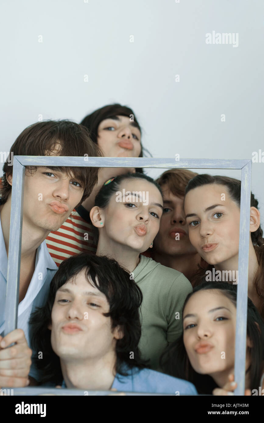 Group of young friends posing for photo, holding up picture frame ...
