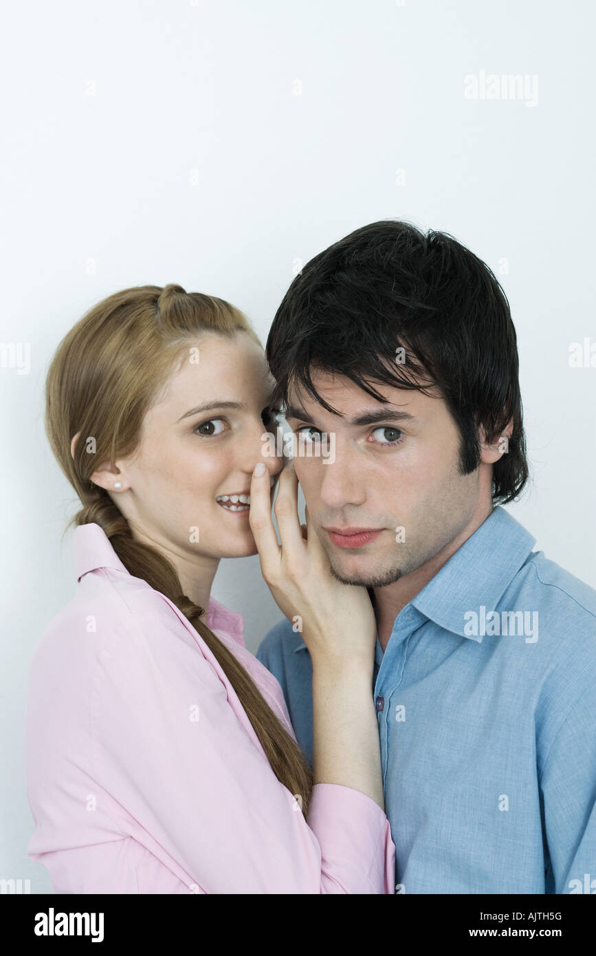 Young couple, woman whispering to man, both looking at camera, portrait ...