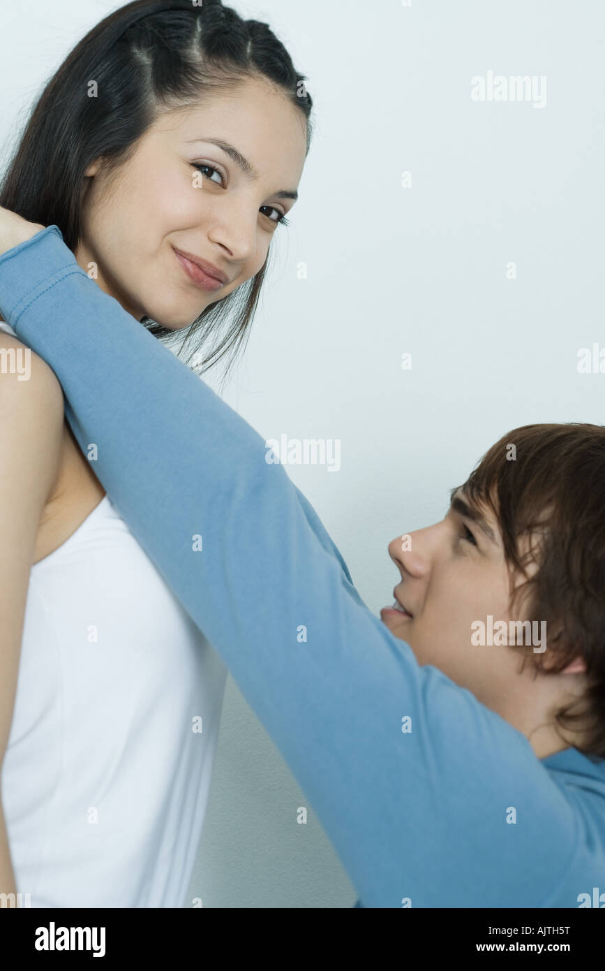 Young couple, man reaching up, putting arms around woman's shoulders ...