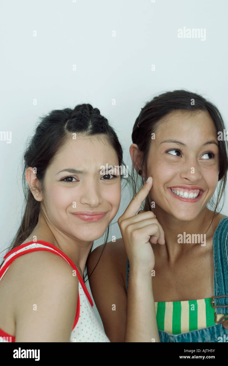 Two young female friends, one furrowing brow at camera, the other ...