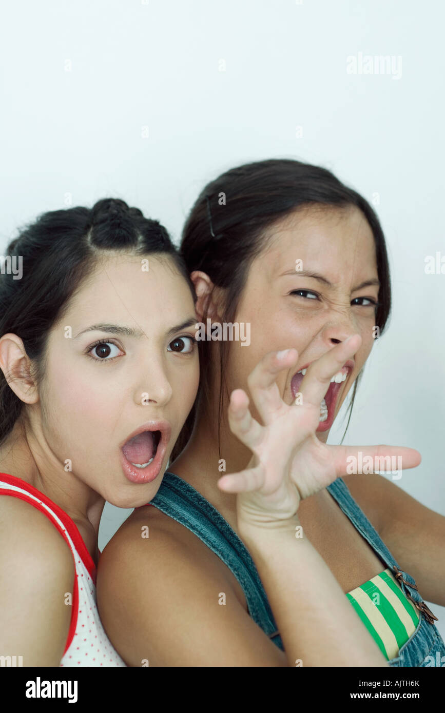 Two young female friends, one snarling at camera, the other with mouth ...