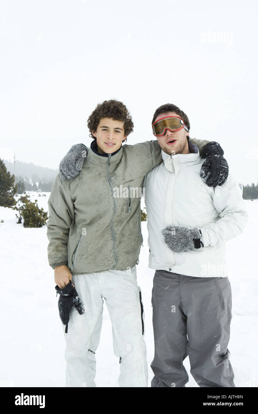 Two Young Skiers Standing With Arms Around Each Others Shoulders Smiling At Camera Portrait