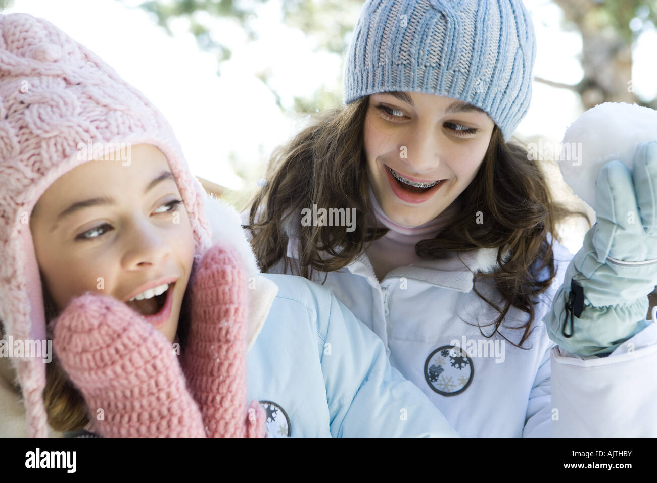 Two teenage girls smiling, one holding up snowball, both dressed in ...