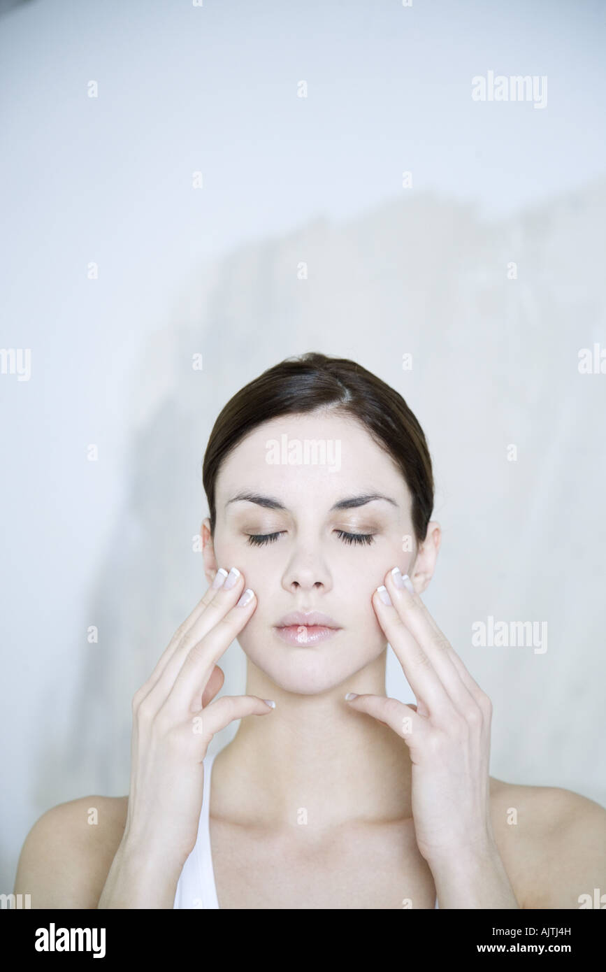 Young woman touching cheeks, eyes closed, portrait Stock Photo - Alamy